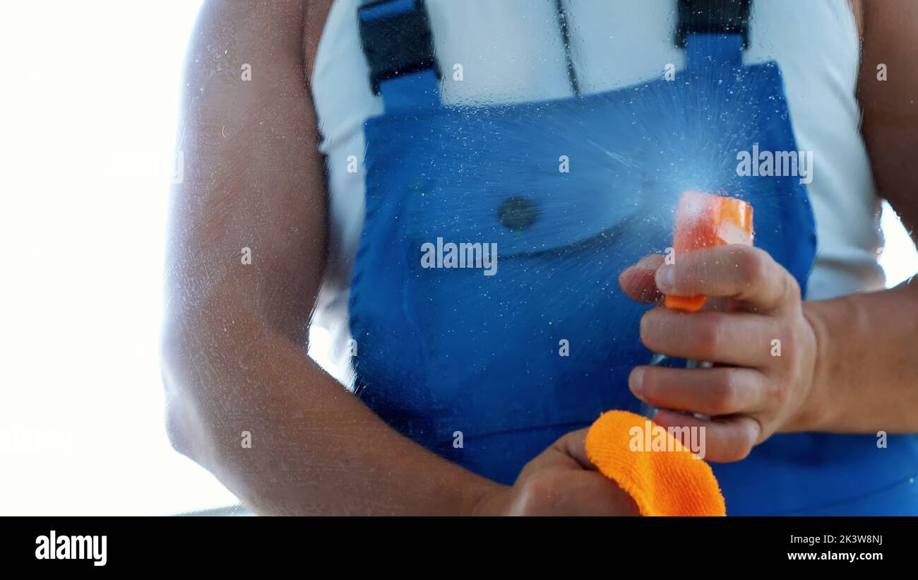 close-up, view through window, male cleaning service worker, in blue ...