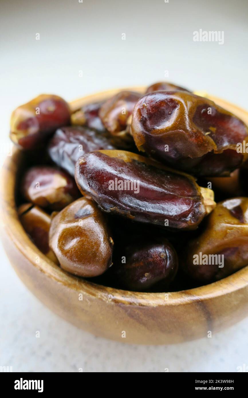 Sweet dried dates in a wooden cup on a white background Stock Photo - Alamy