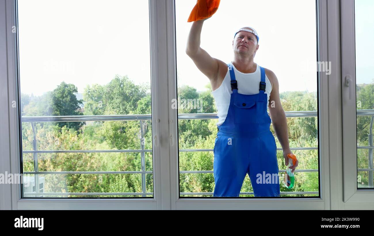 view through window, attractive male cleaning service worker, in blue ...