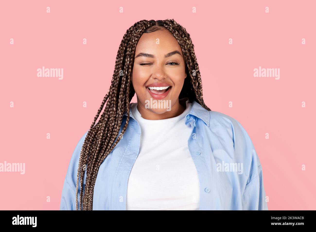 Portrait Of Playful African Woman Winking Eye Over Pink Background ...