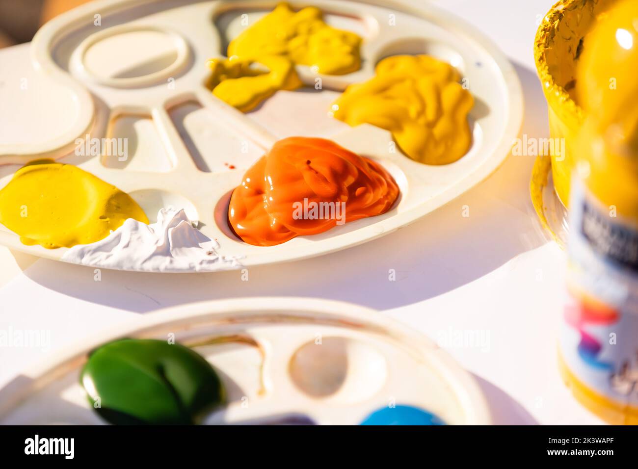 paints and brushes in the process of work, palette with mixed paints ...