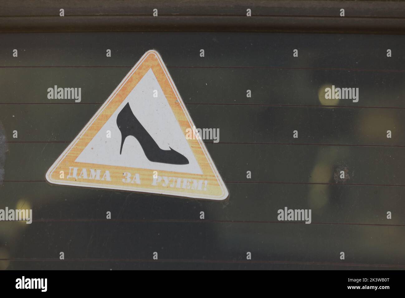 Joking road sign "woman at the wheel " on the rear window of the car ...