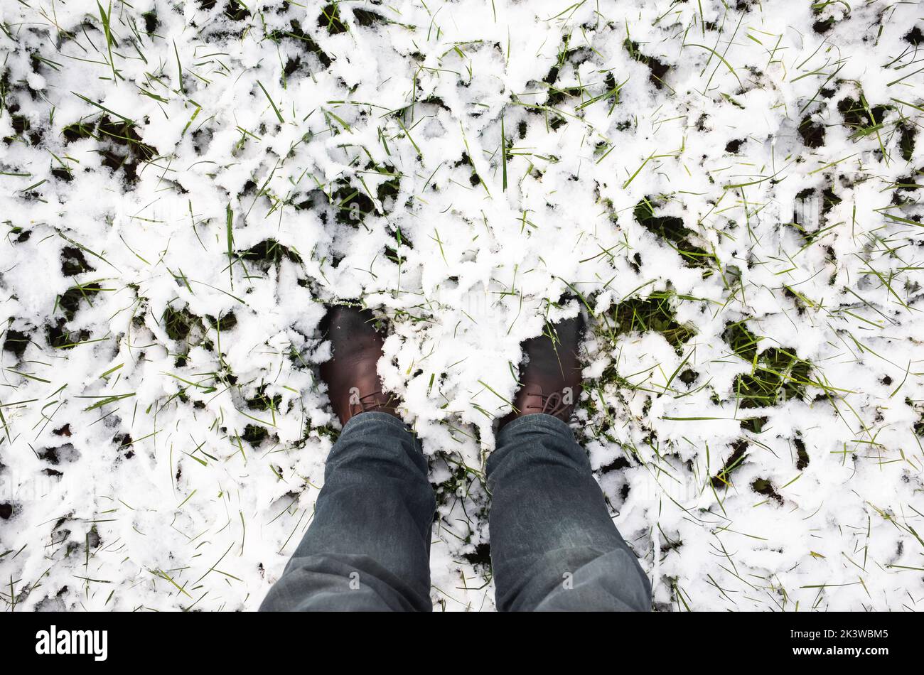 Feet of a man standing in fresh snow, top view, first person look ...