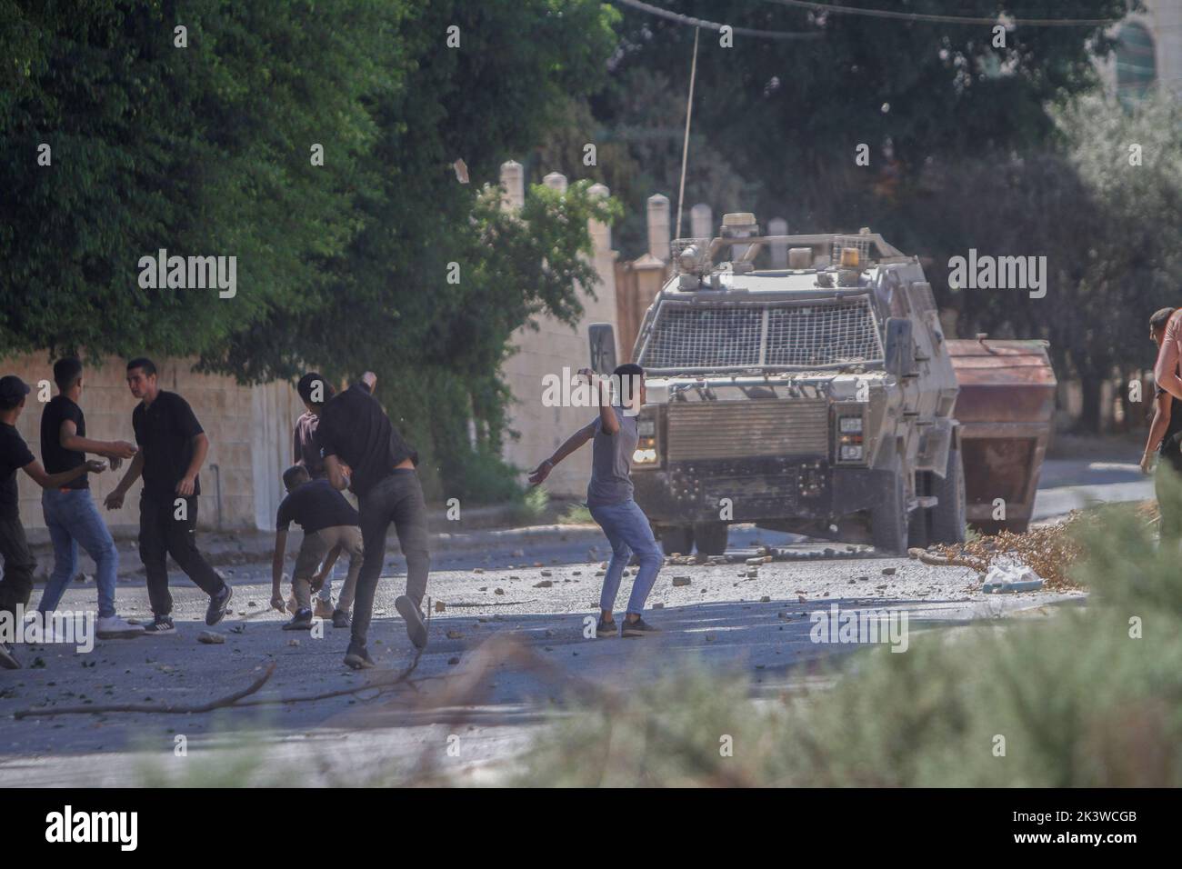 Palestinian protesters throw stones at the Israeli army vehicles ...
