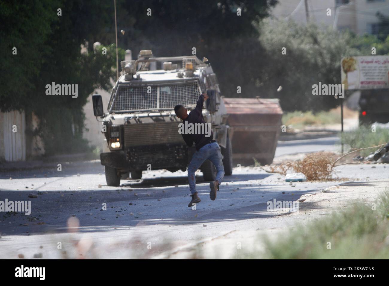 Palestinian protesters throw stones at the Israeli army vehicles ...