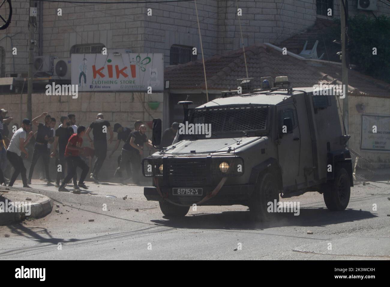 Palestinian protesters throw stones at the Israeli army vehicle ...