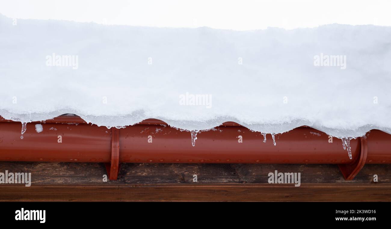 Snow falling from the roof of the house. Winter weather with heavy ...