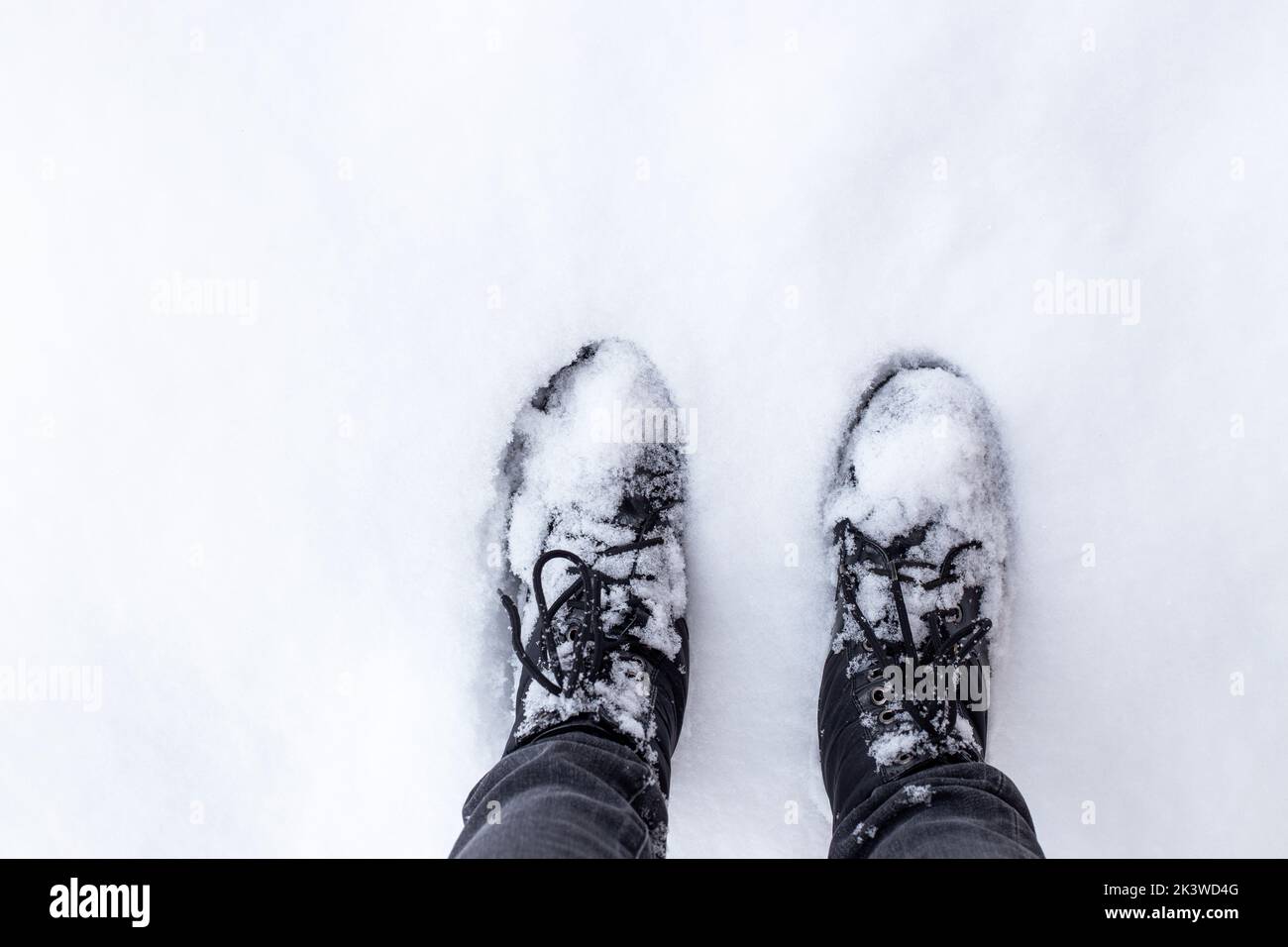 feet in black boots on snowy ground. The arrival of winter and snowy ...