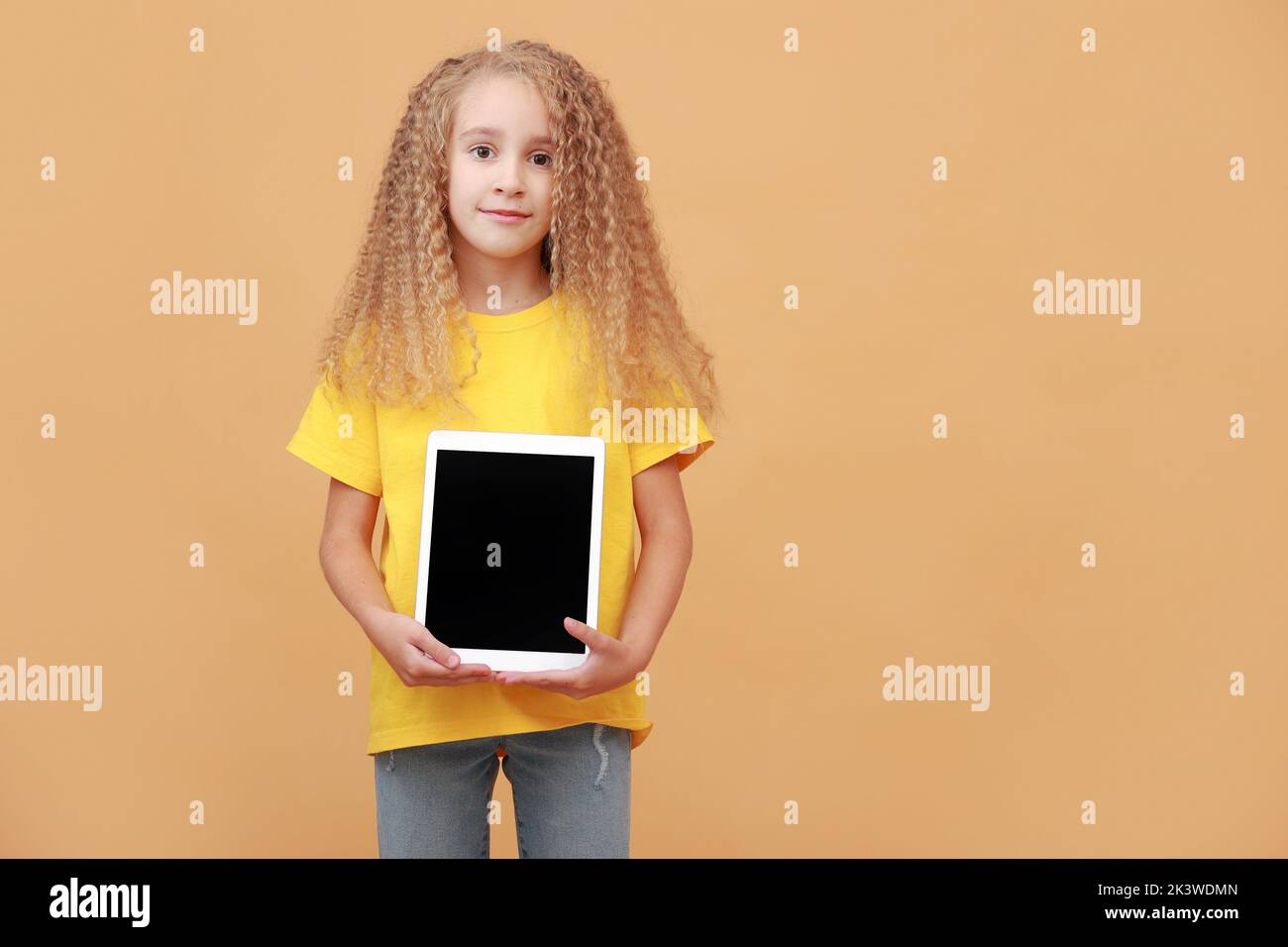 smiling curly child girl with tablet in hands isolated on background ...