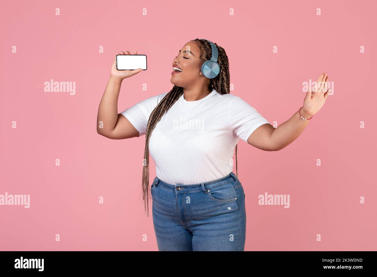 Black Plus Size Lady Singing Holding Cellphone Wearing Headphones ...