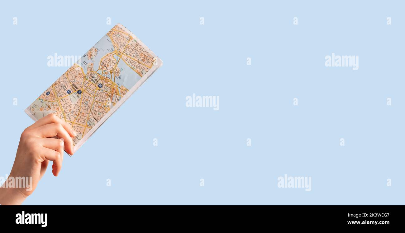 Paper map, travel guide in hand on blue background. High quality photo ...