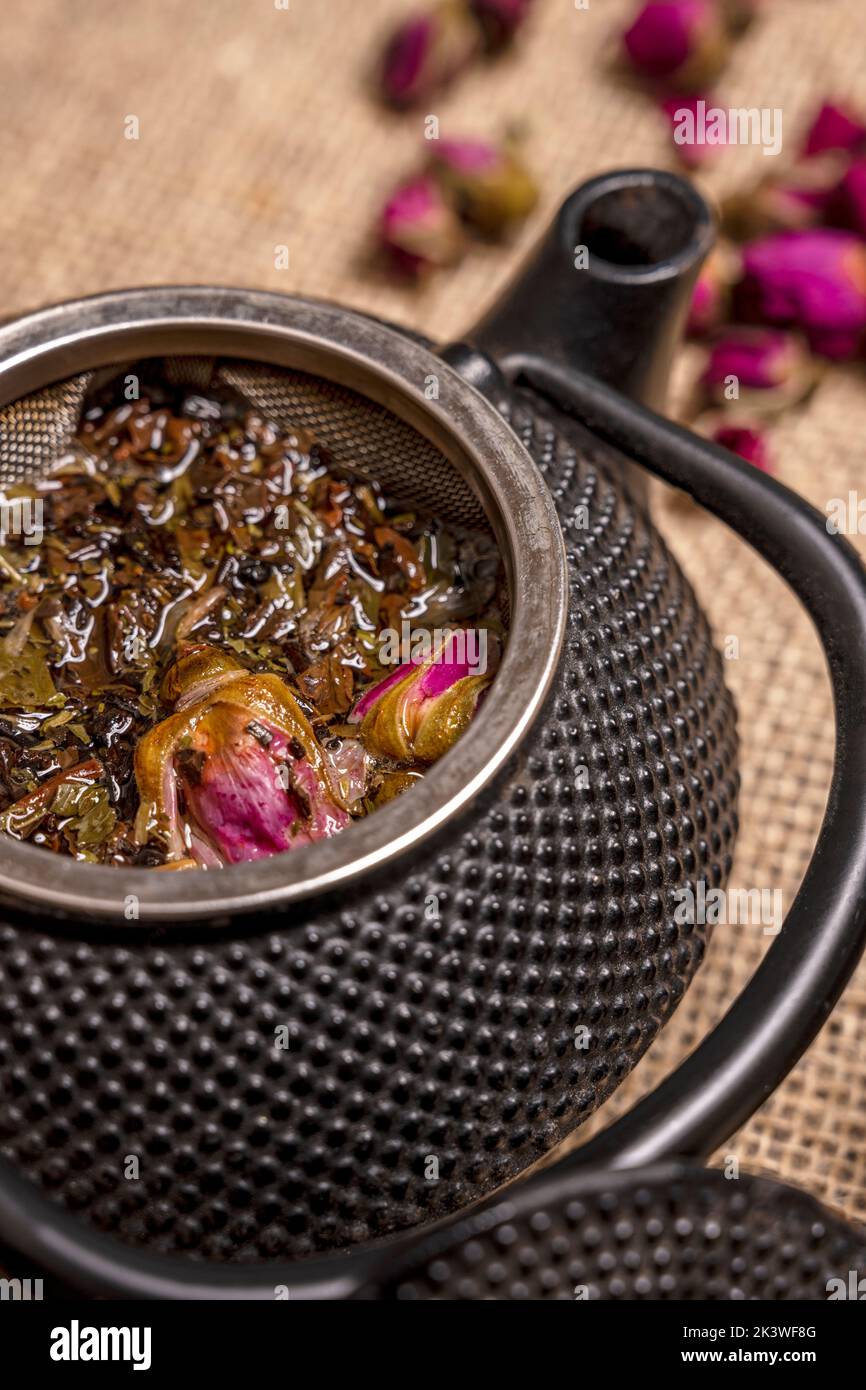 Inside closeup of an asian style black metal teapot with rose tea and ...