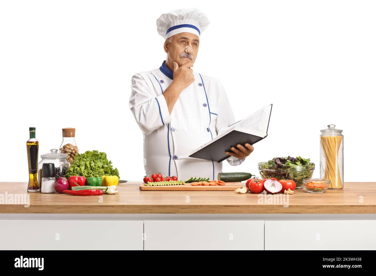 Mature male chef in a uniform holding a cook book and thinking what to ...