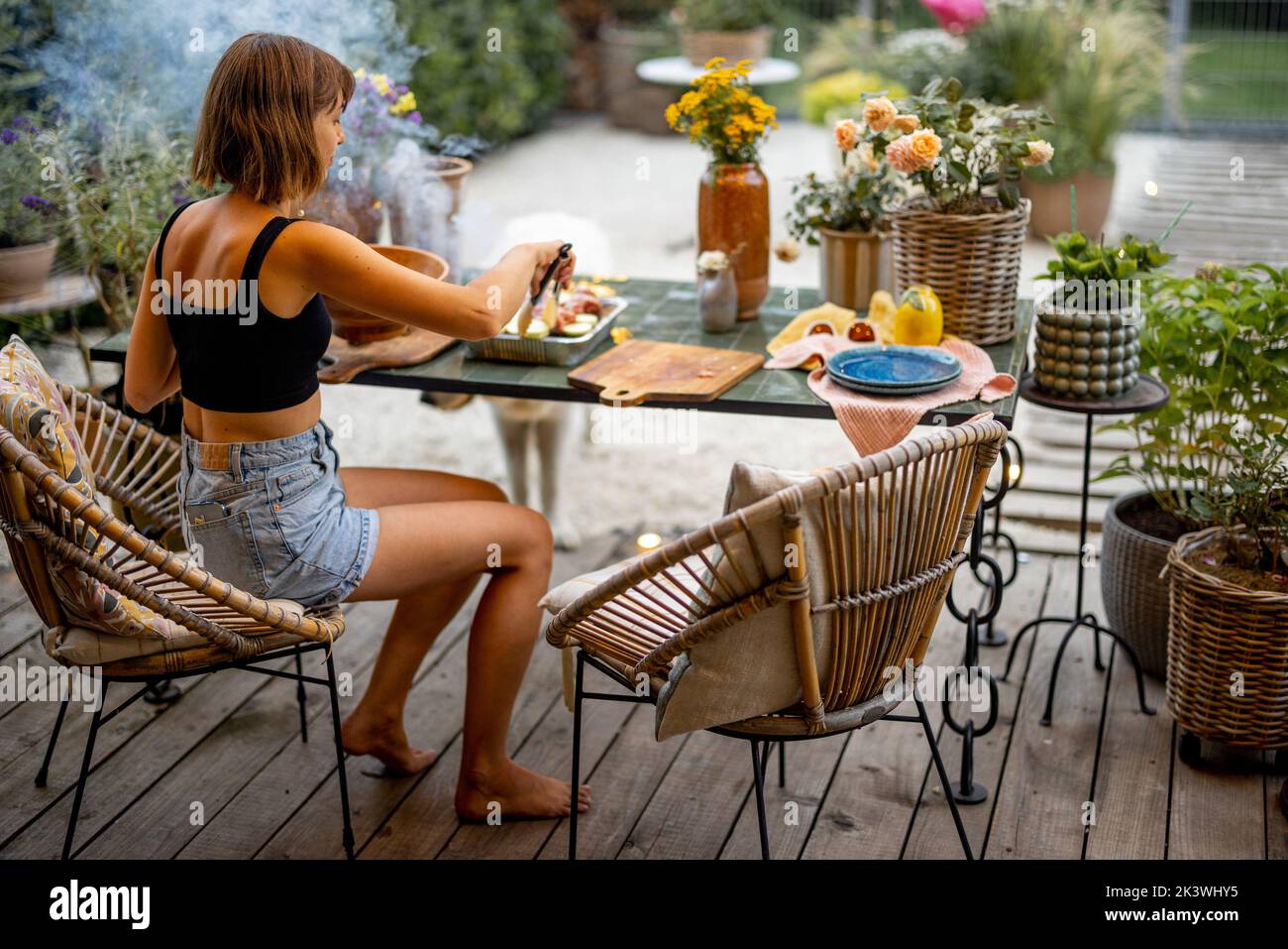 Woman having a dinner on terrace at backyard Stock Photo - Alamy