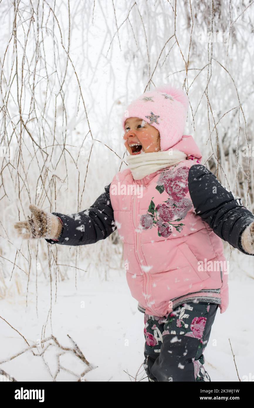 Little girl with ruddy cheeks and wide extremely happy smile in warm ...