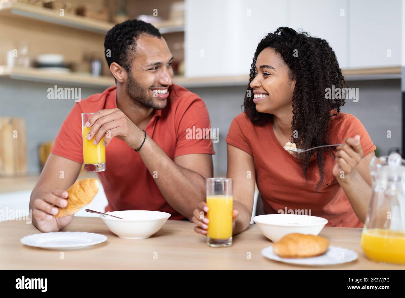 Laughing handsome millennial black wife and husband enjoy breakfast ...