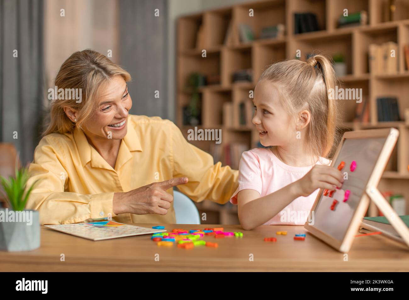 Excited woman speech therapist teaching adorable little girl alphabet ...