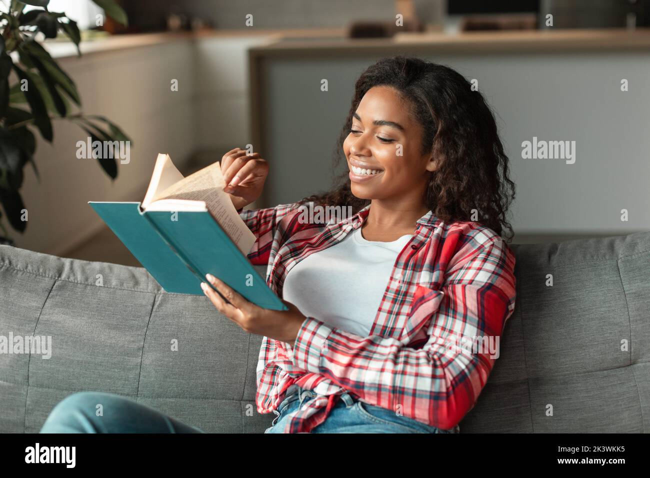 Happy smart pretty millennial african american woman sitting on sofa ...