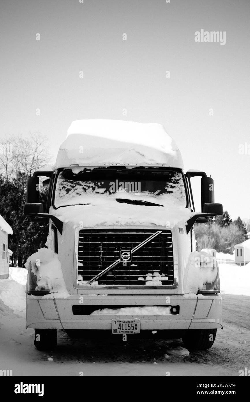 A vertical grayscale shot of a Volvo truck covered in snow on the ...