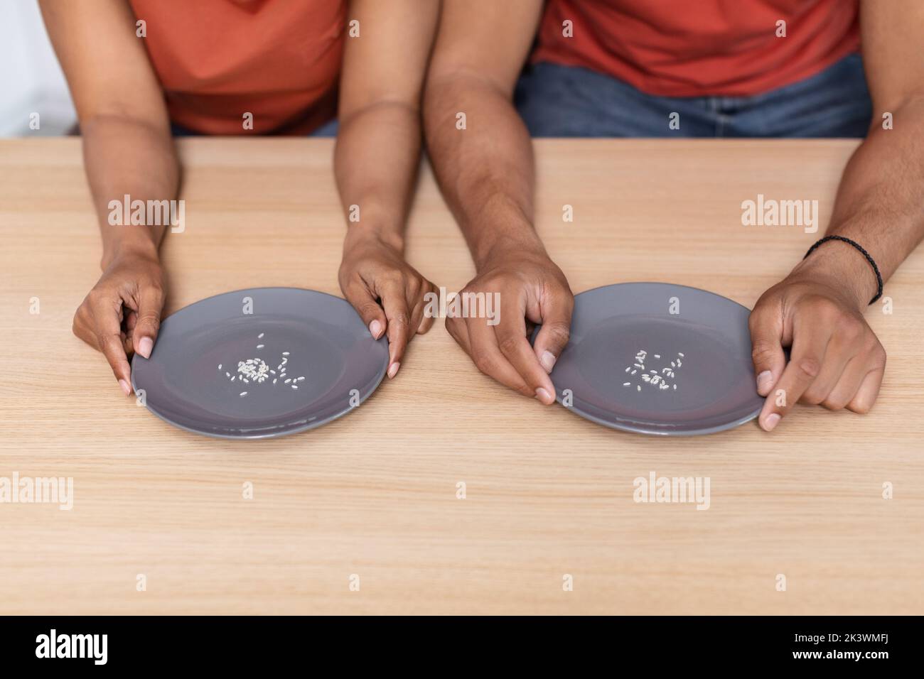 Despaired young black man and woman holding plates with several grains ...