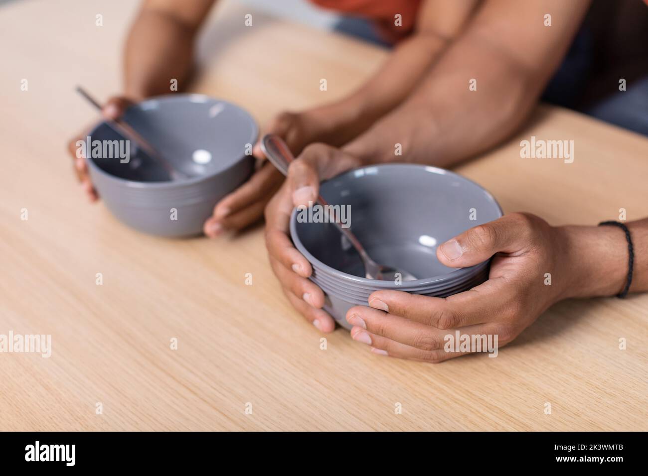 Sad millennial black wife and husband holding empty plates on wooden ...