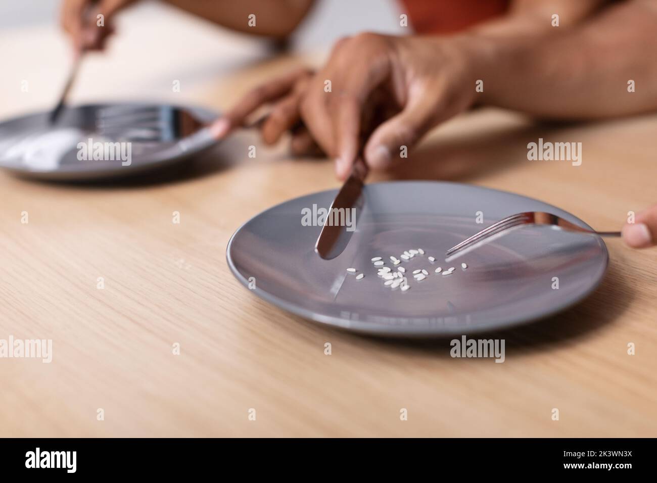 Millennial black couple, with plates and cutlery eat several grains of ...