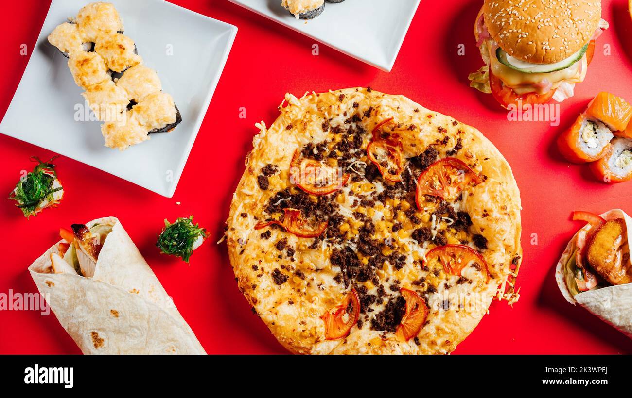 A top view of fast food delicacies including pizza, burger, wraps and ...