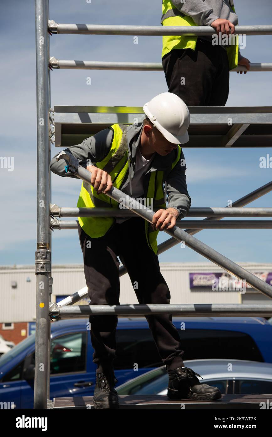 A vertical shot of Workers wearing PPE building outside scaffolding ...