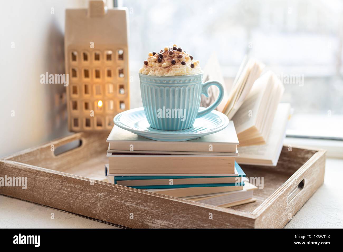 Coffee cup with whipped cream and open book on a window sill. Concept ...