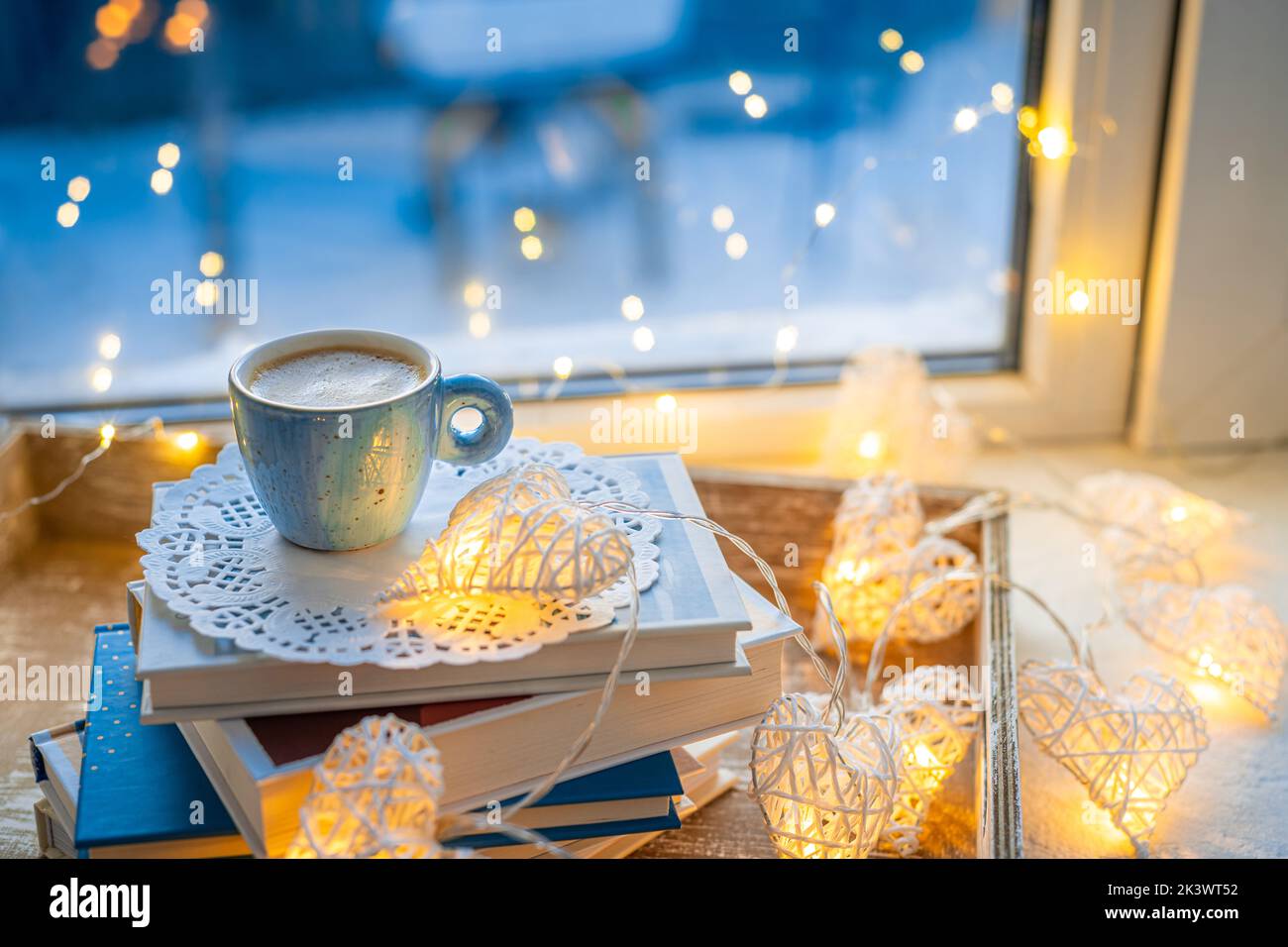 Coffee cup, books, sparkle fairy lights on window sill on blurred ...