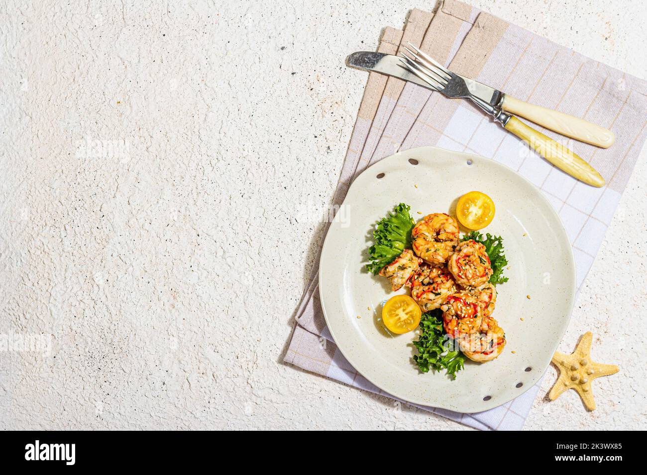 Grilled shrimp salad with lettuce, tomato cherries and spices on a ...