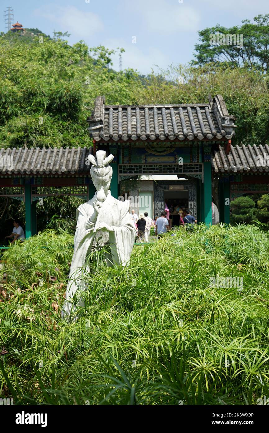 A vertical shot of a white statue standing outdoors with trees around ...