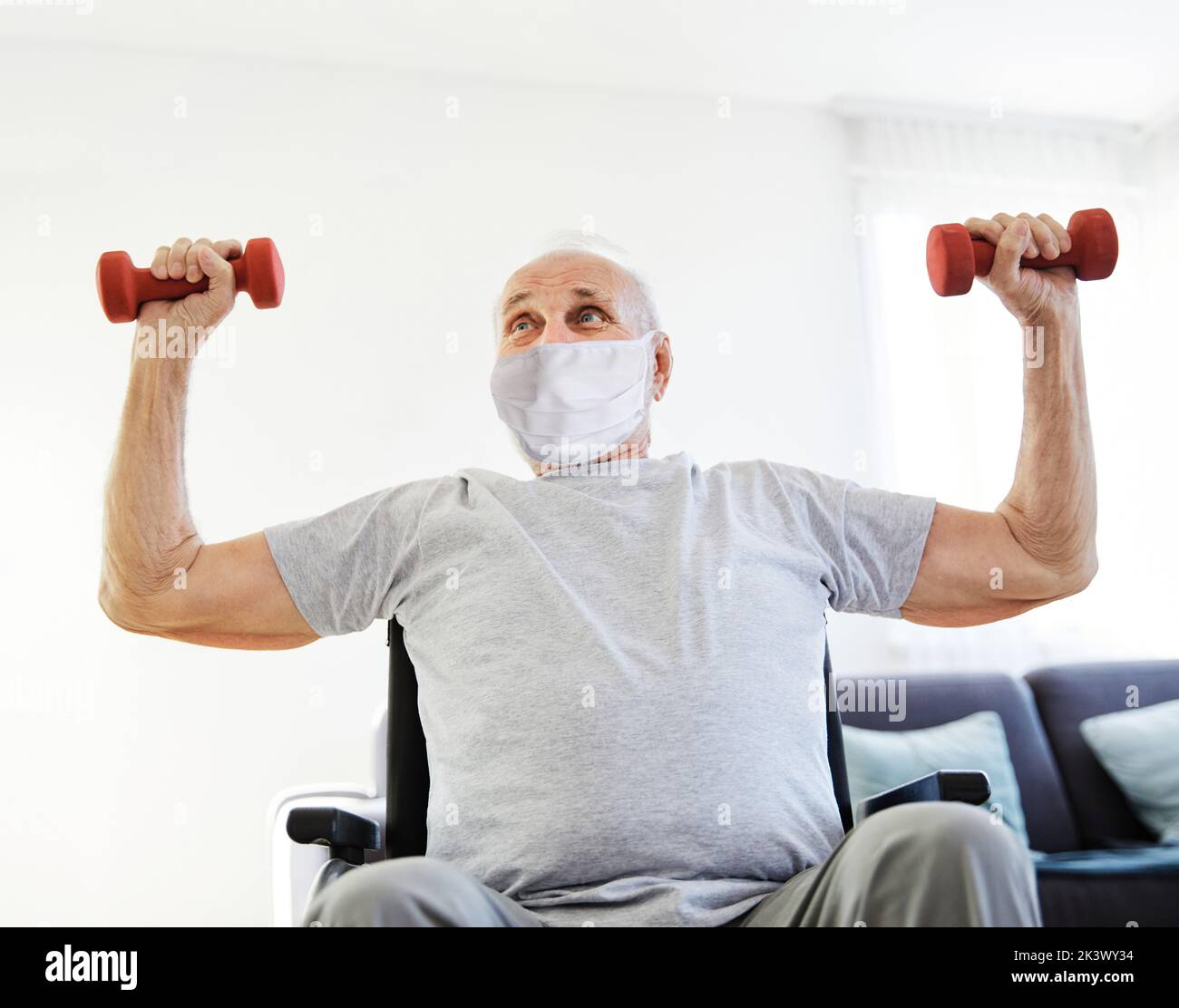 Happy senior man in wheelchair wearing protective mask exercising at home or nursing home Stock ...