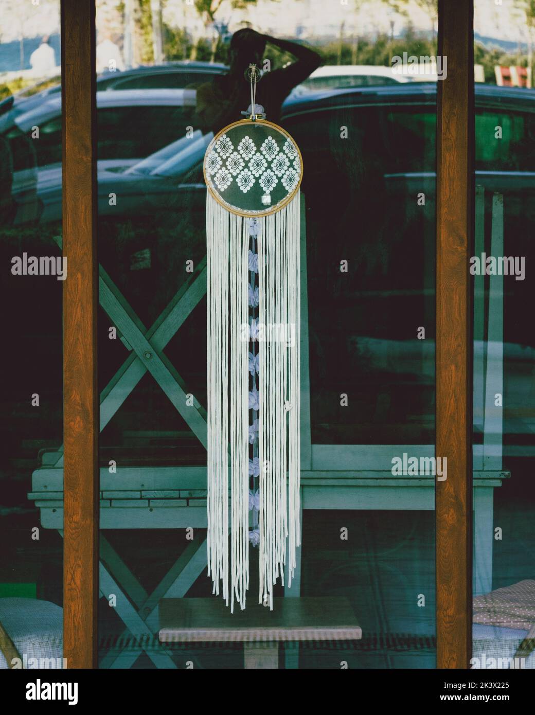 A vertical shot of a macrame dreamcatcher on a glass window Stock Photo ...