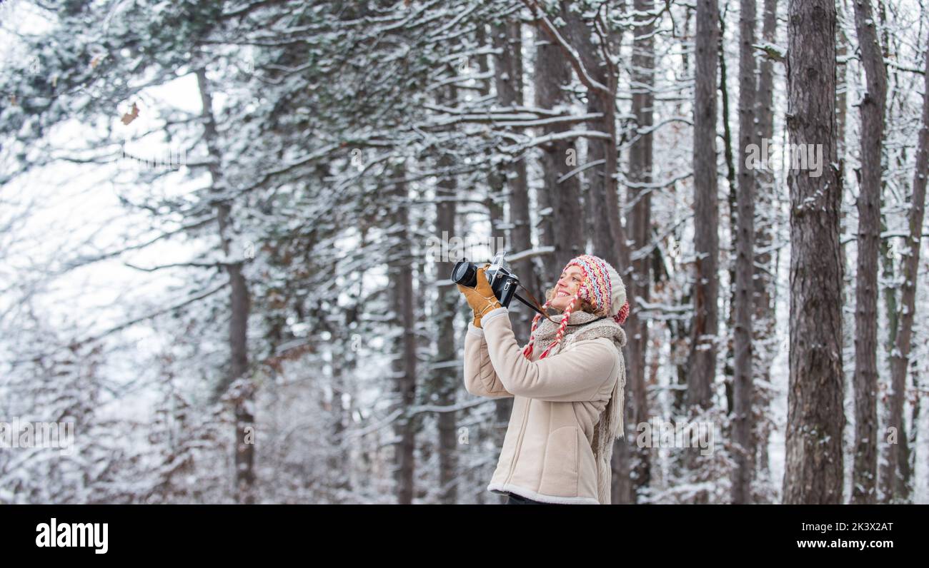 Enjoy beauty of snow scenery through photos. Woman photographer with professional camera ...