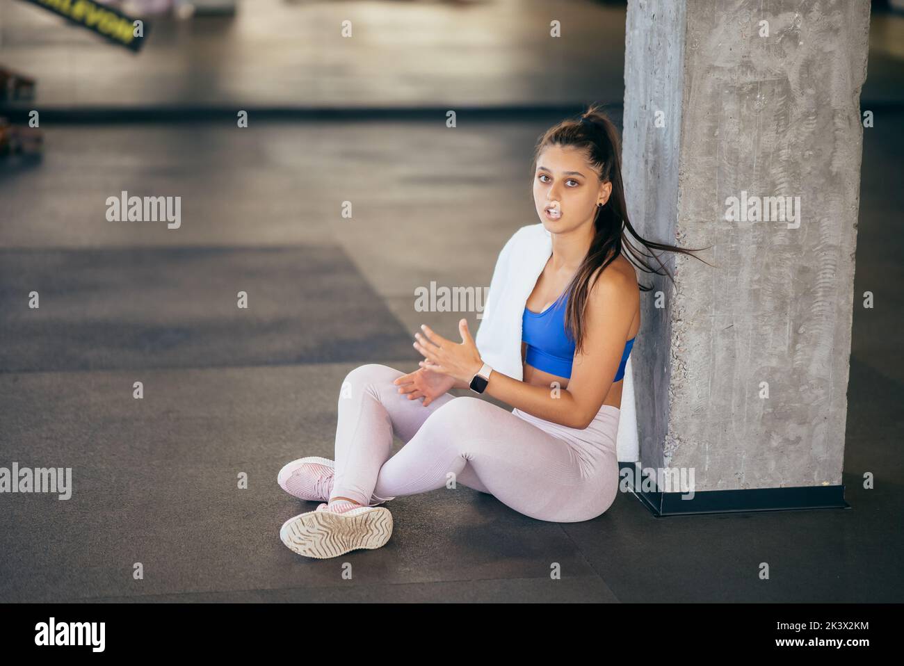 Healthy young female sitting relaxed after training in gym Stock Photo ...
