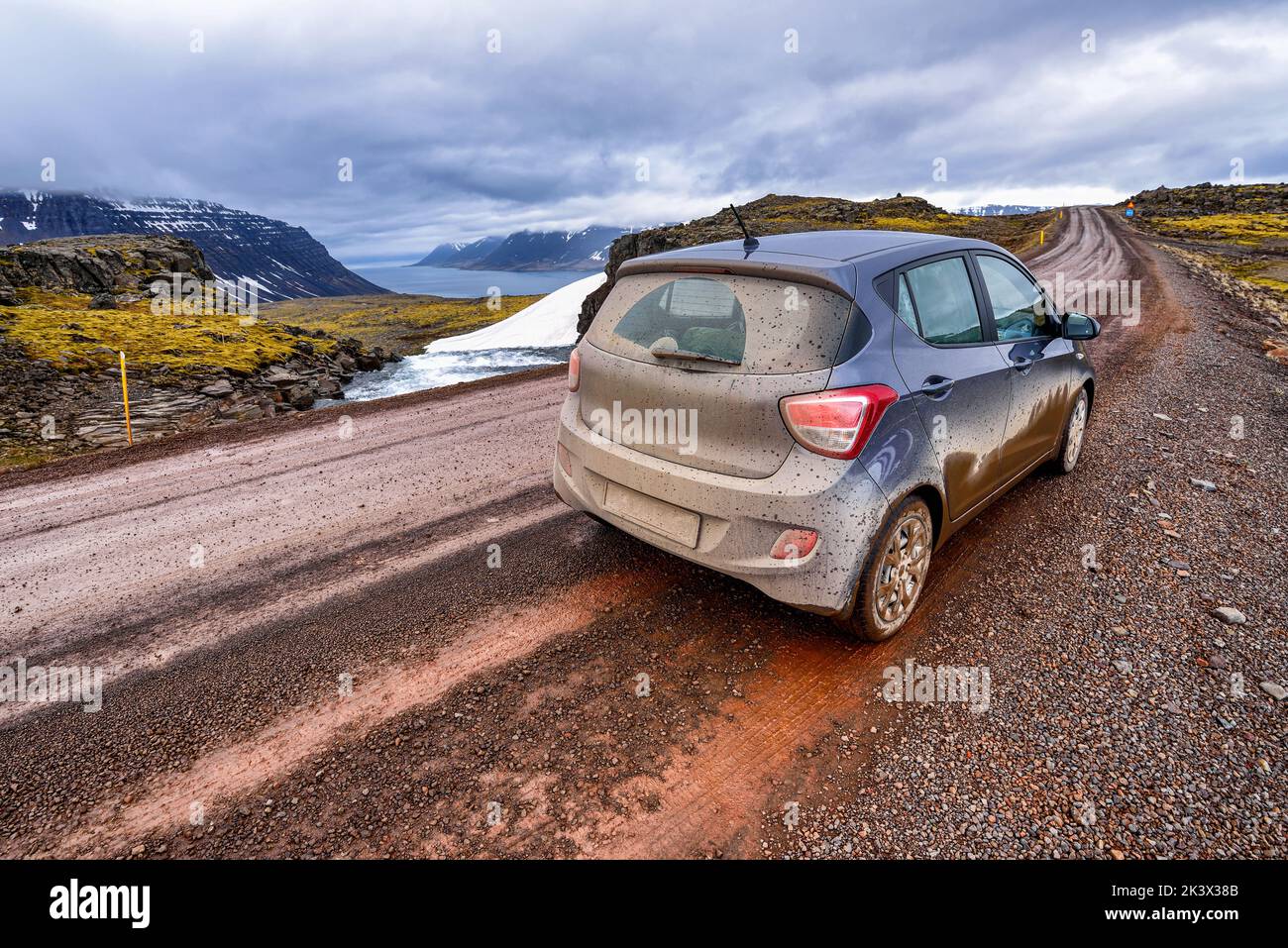 Car full of red mud on a muddy gravel road in Iceland under an overcast ...