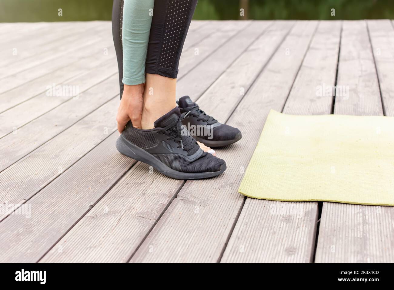 the feet of a girl taking off her black sneakers in front of a green ...