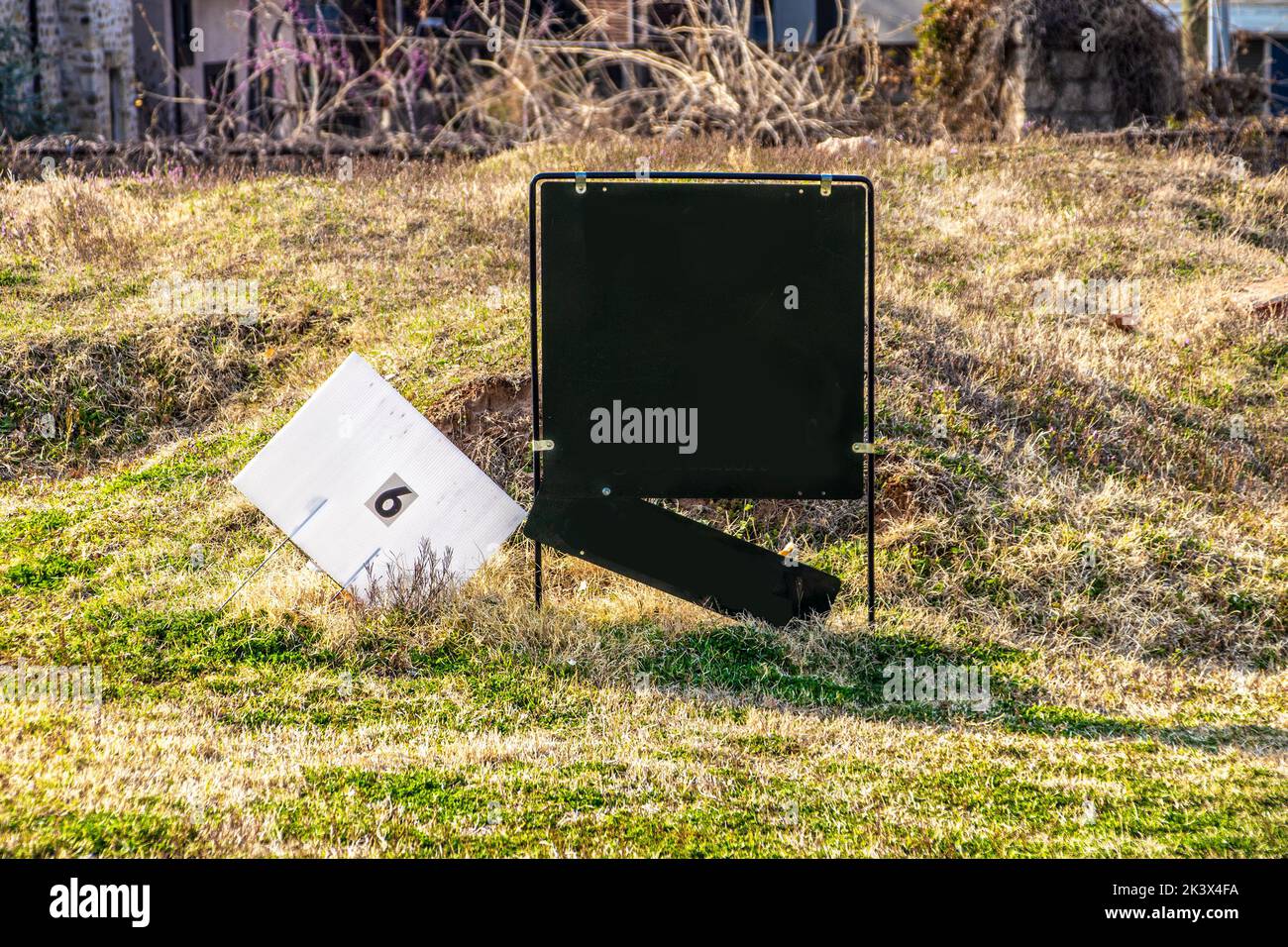 Black realtor's sign with hanging name sign partly broken off and lot ...