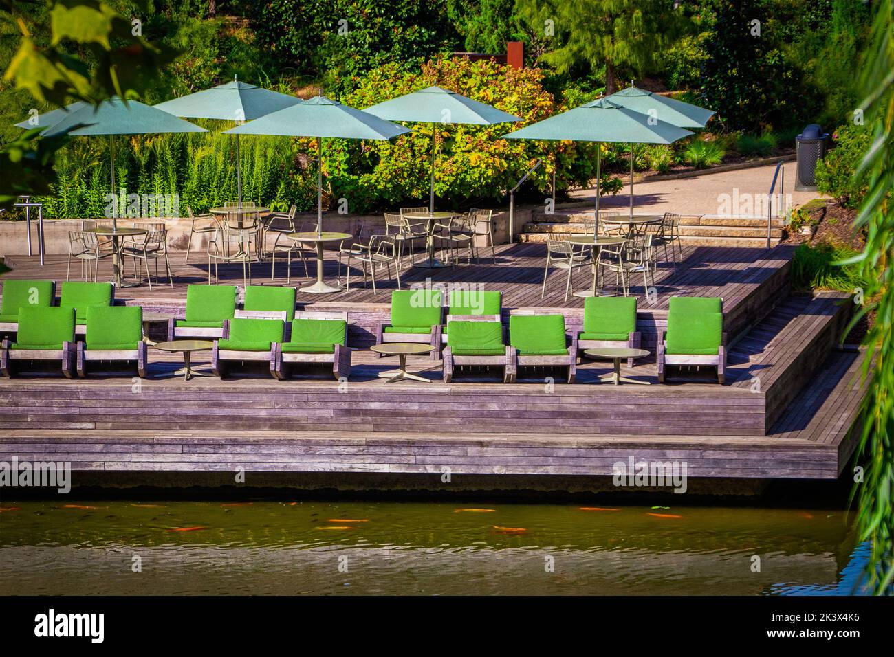 Large wooden deck by water with tables and umbrellas and green ...