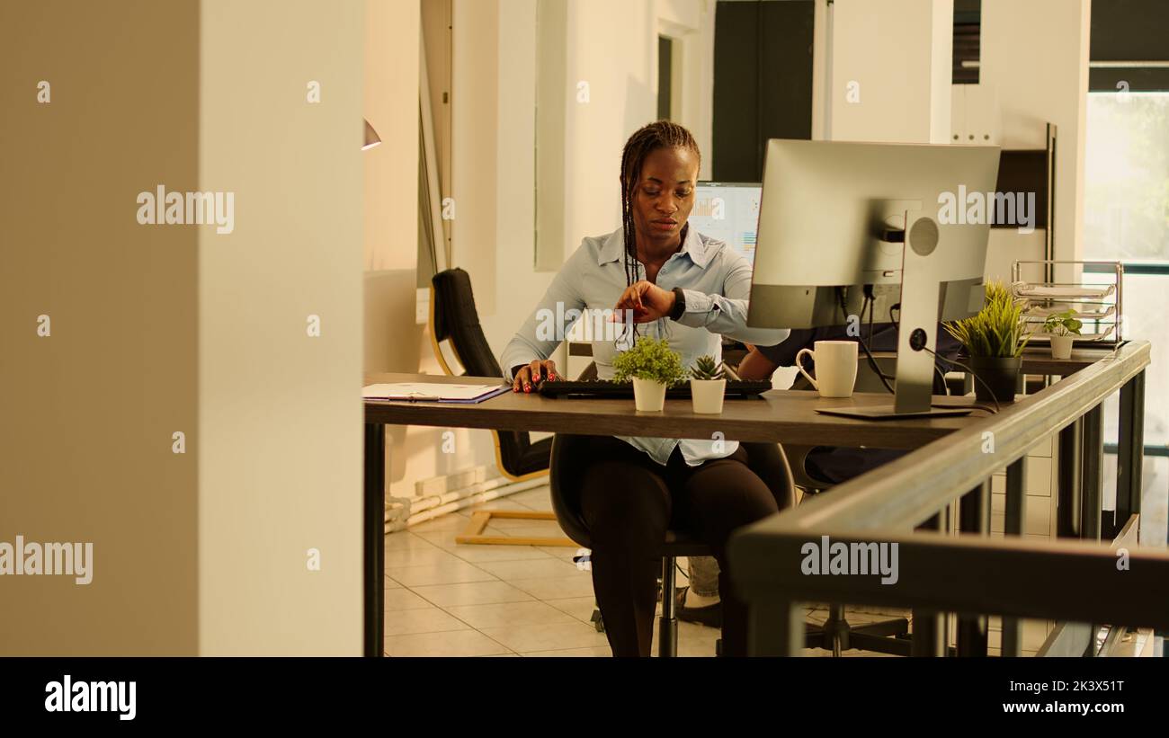 Business woman checking time on wristwatch at startup job in office ...