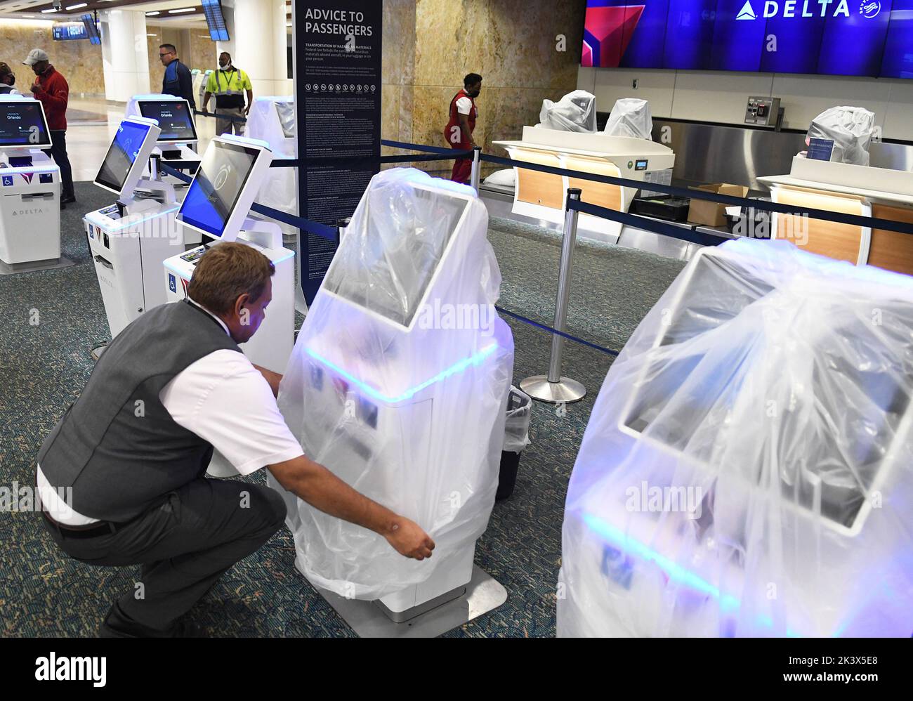 Delta Airlines employee Juan Martinez covers a check-in kiosk with a ...