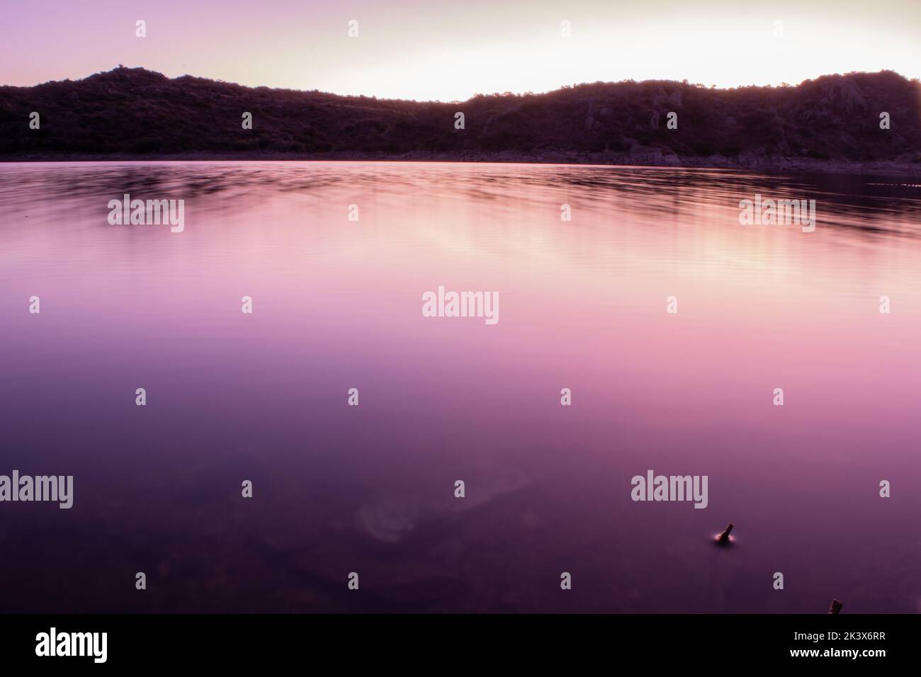 A landscape with lagoon and mountain ranges in a dam with a pink ...
