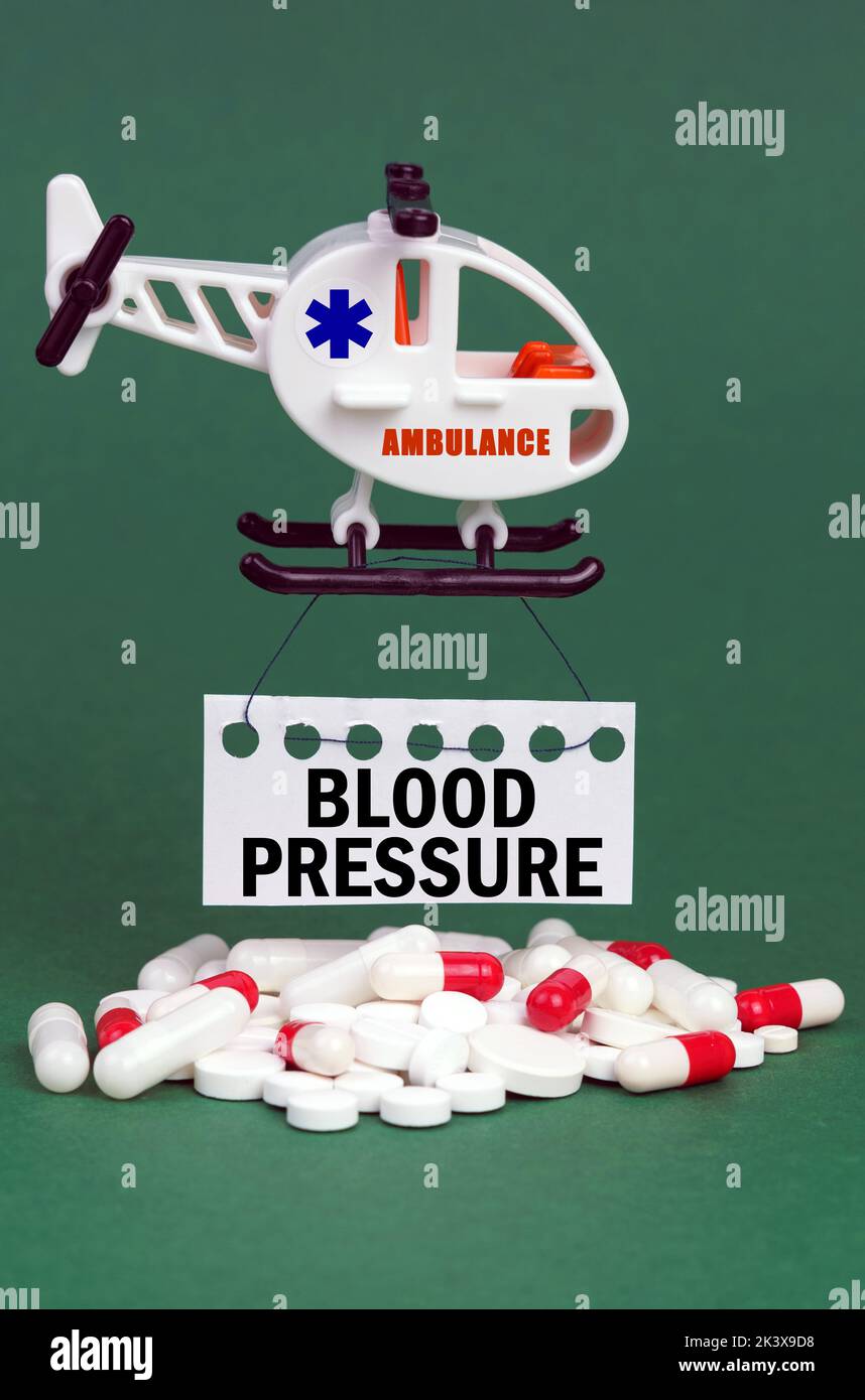Medical concept. On a green surface, an ambulance helicopter, pills and ...