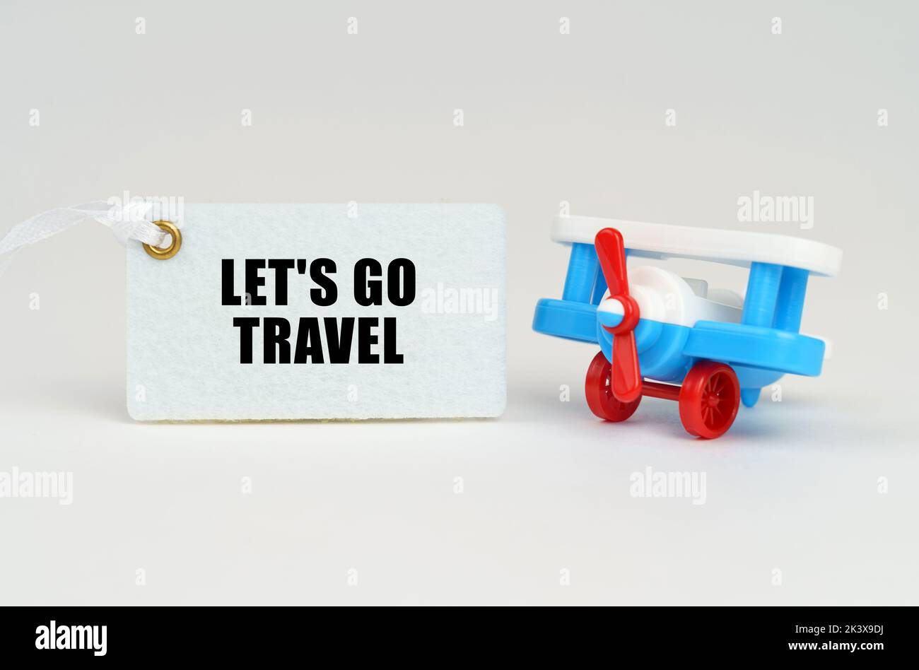 On a white surface there is a toy airplane and a sign with the ...