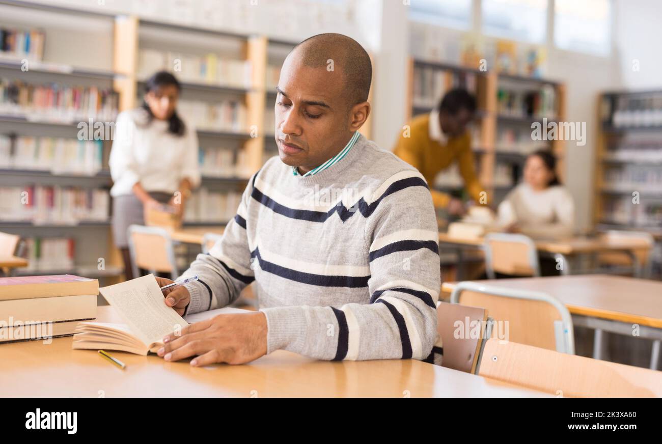 Young adult man studying in public library Stock Photo - Alamy