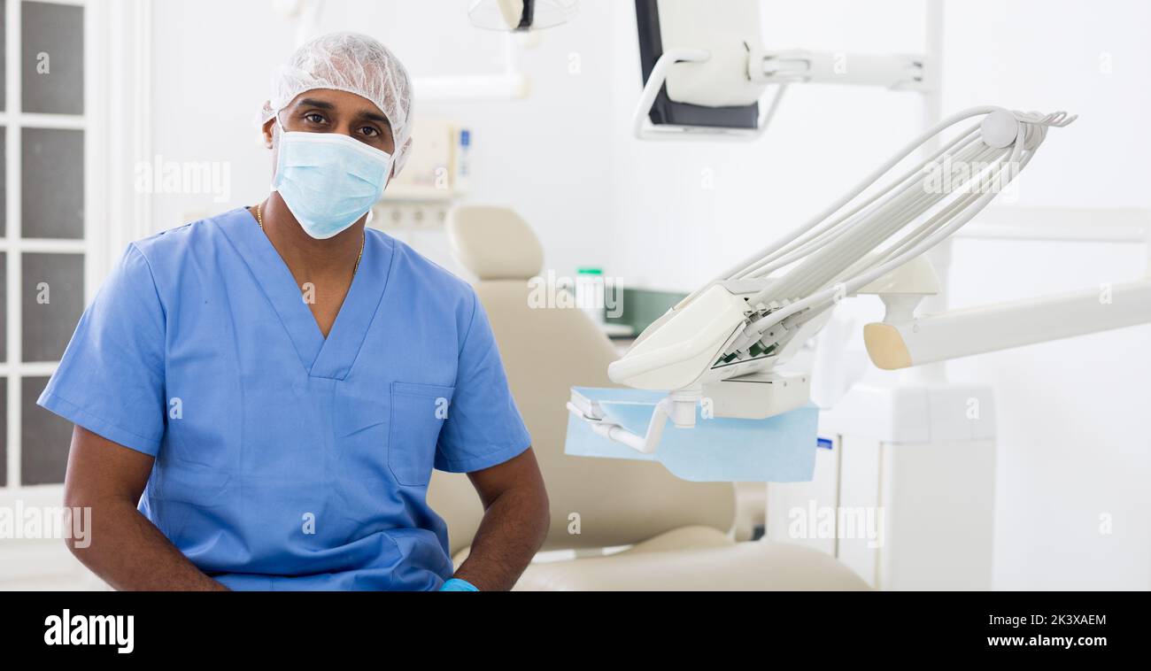 Qualified dentist standing in blue uniform in dental office Stock Photo ...