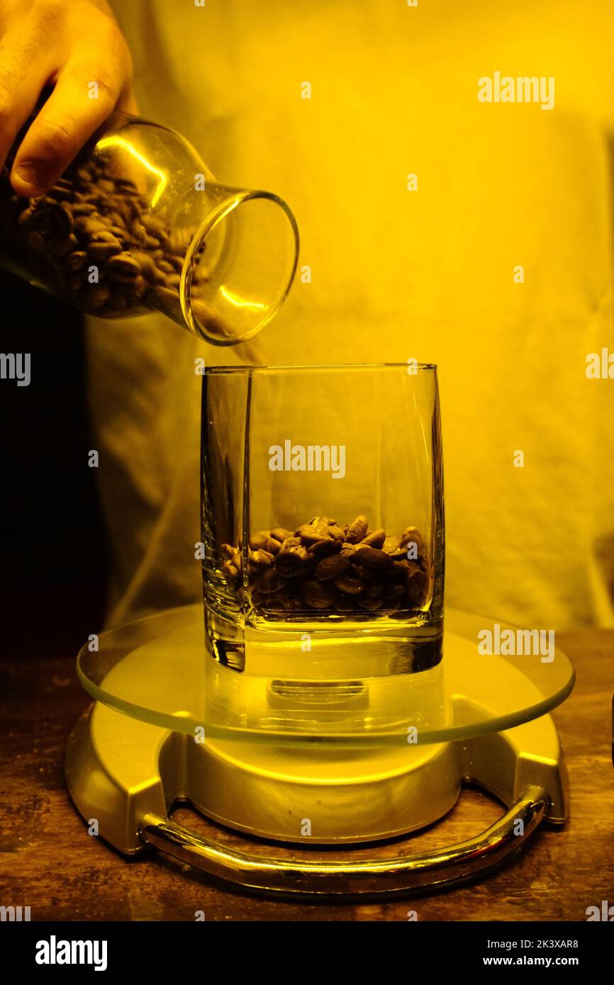 A vertical shot of a barista pouring fresh coffee beans on the kitchen ...