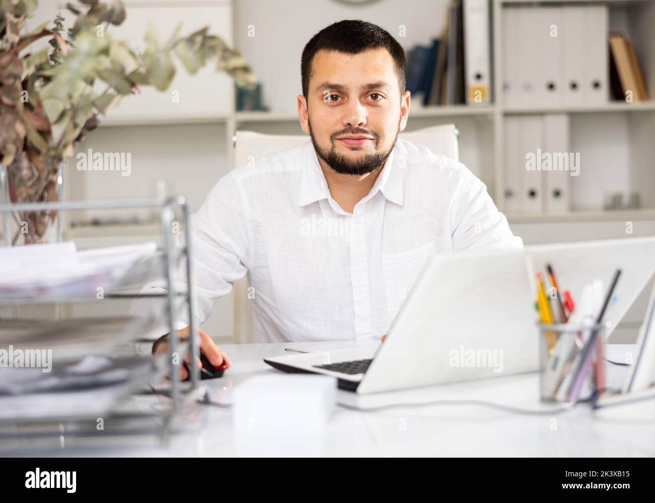 Positive man office worker using laptop during workday Stock Photo - Alamy