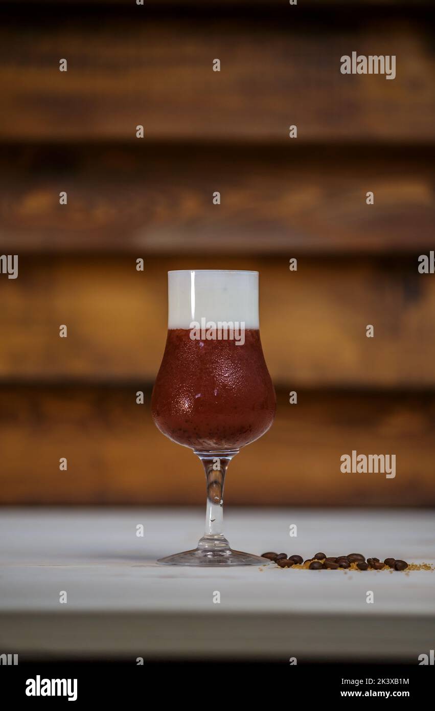 A vertical shot of a glass of Red Purvis beer with coffee on a wooden ...